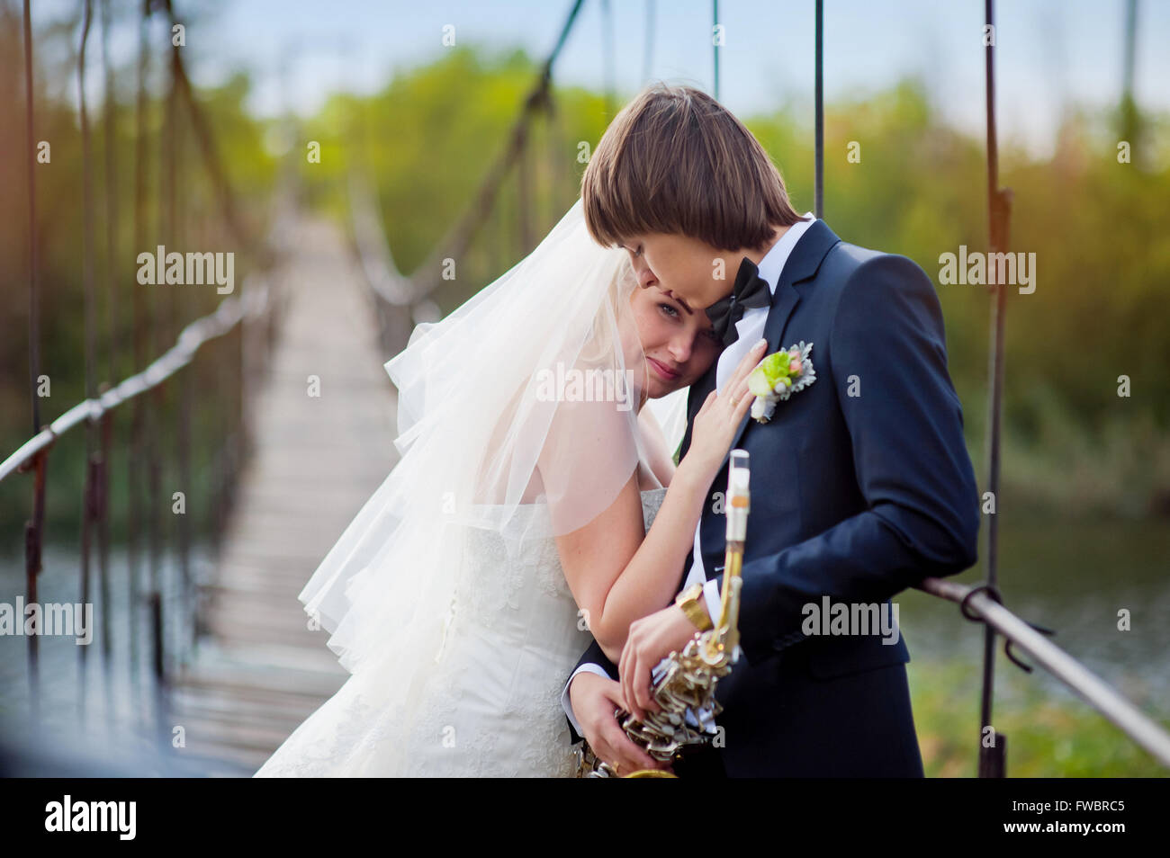 Young happy bride and groom standing on a bridge Stock Photo - Alamy