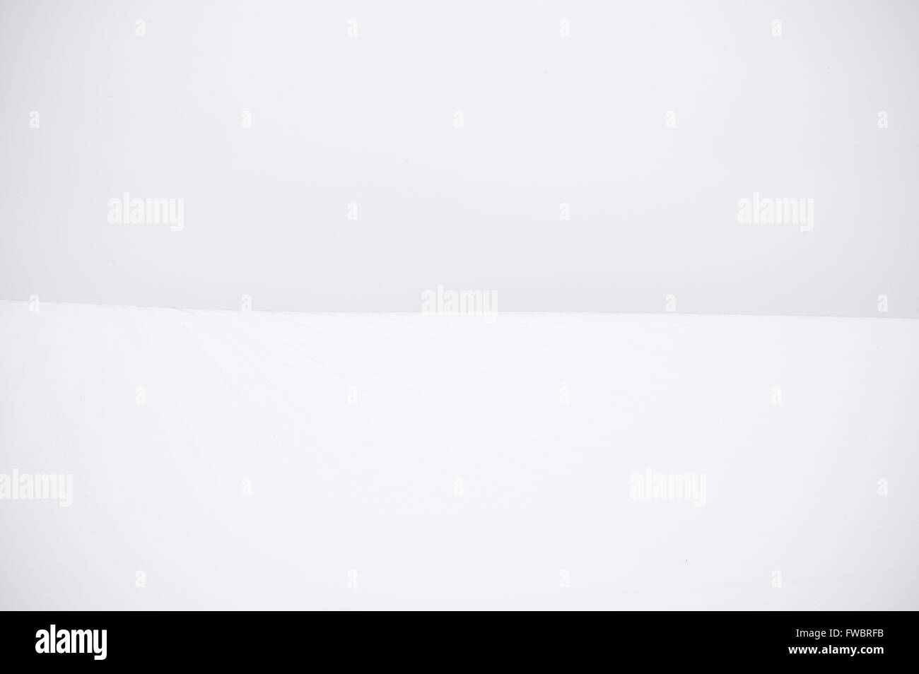 A bare and empty winter landscape showing a hill covered in snow and a ...