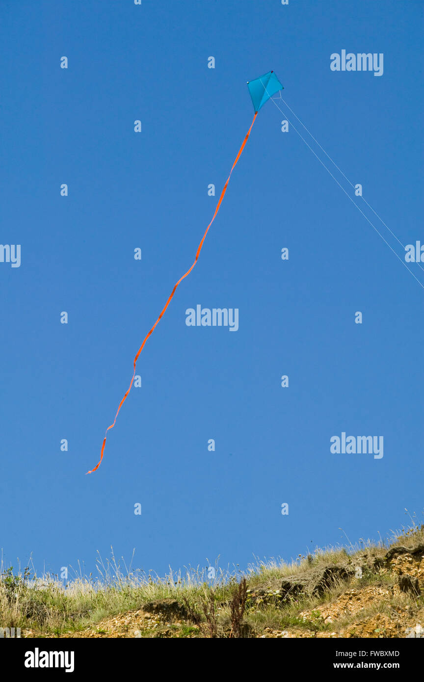 A single kite with ribbon tail flies in abright deep blue sky Stock ...