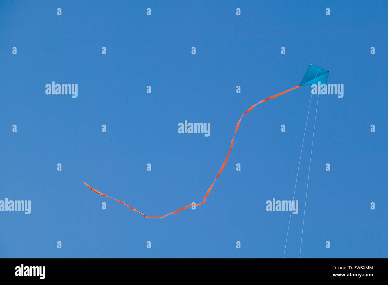 A single kite with ribbon tail flies in abright deep blue sky Stock ...