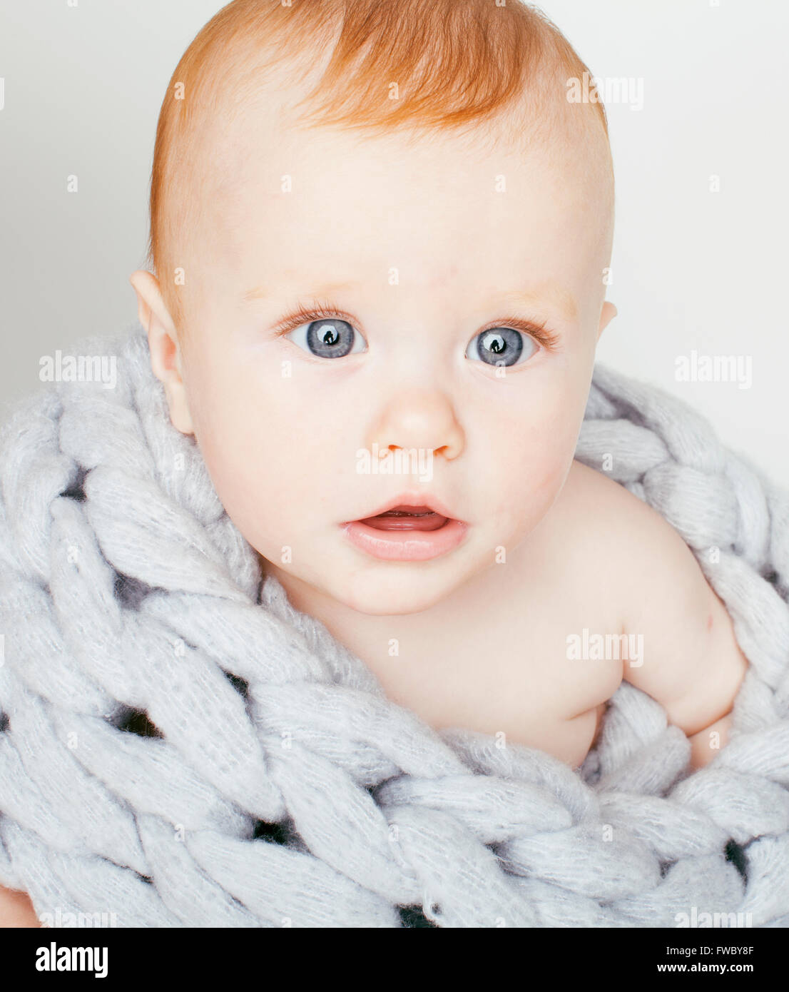 little cute red head baby in scarf all over him close up isolated ...