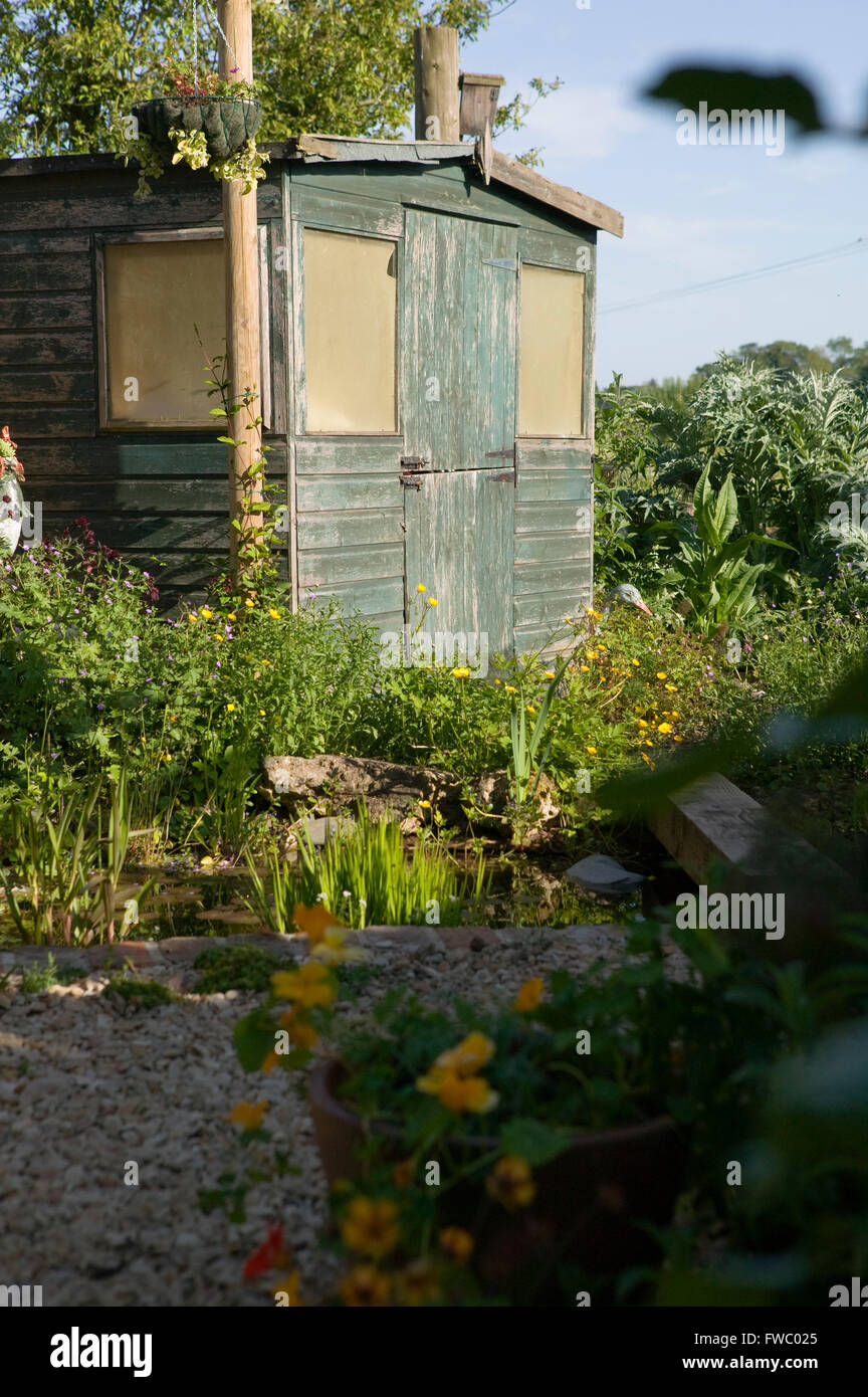 Landscape view of a small garden with pond, shed, ornaments and ...