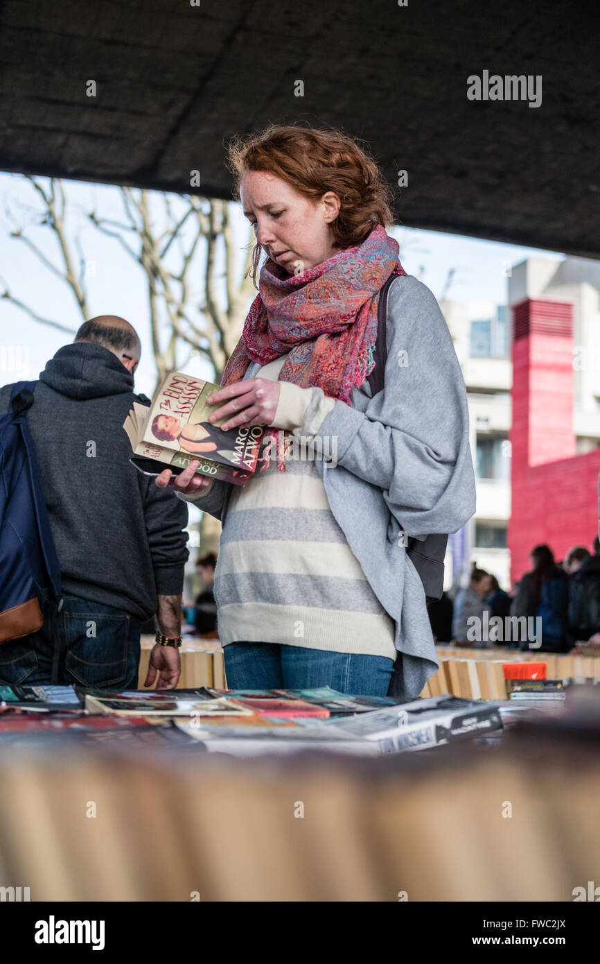 A young woman browses books at an outdoor used book market in London ...