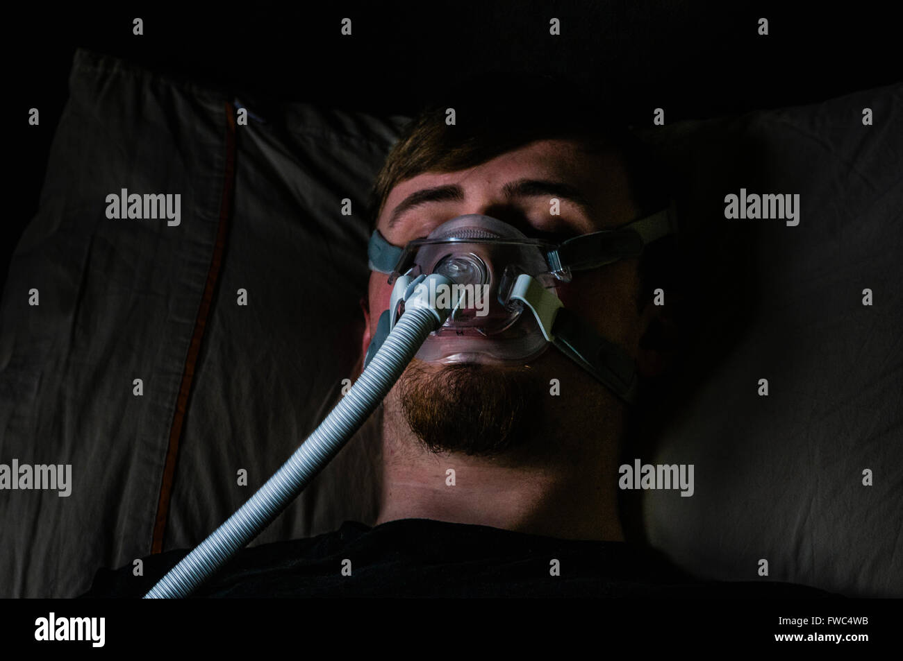 A man in bed at night using a Philips Respironics System One CPAP ...