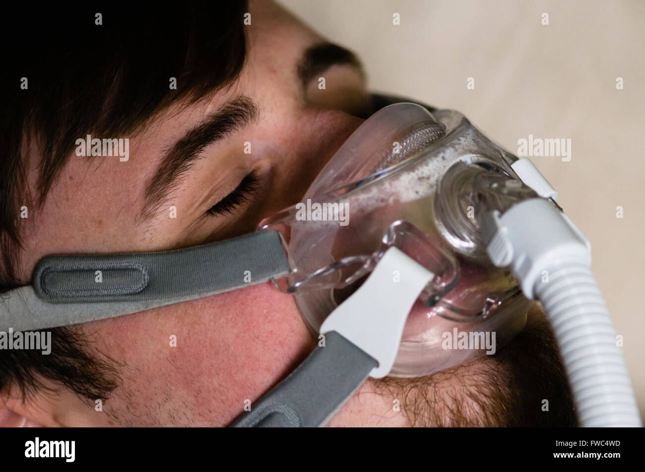 A man in bed at night using a Philips Respironics System One CPAP ...