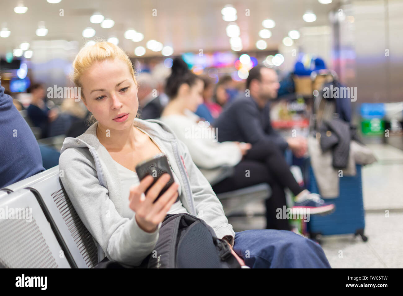 Female traveler using cell phone while waiting Stock Photo - Alamy