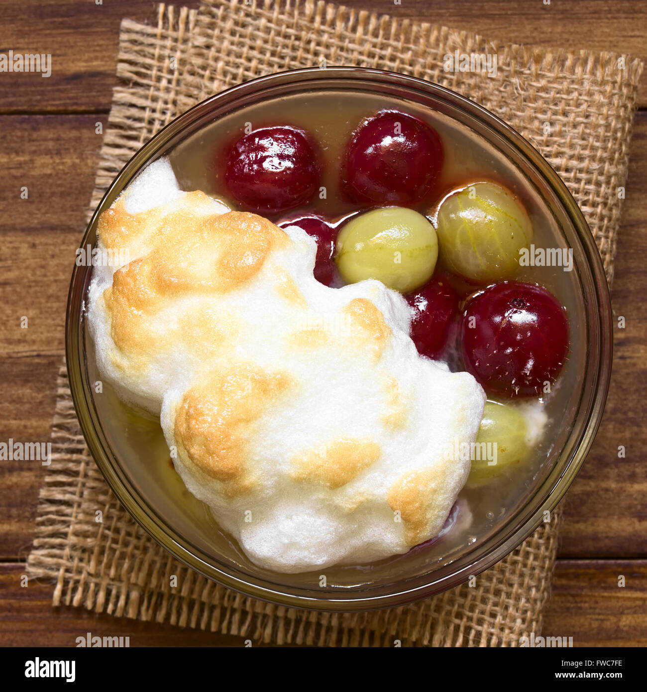 Stewed red and green gooseberry dessert with meringue in glass bowl ...