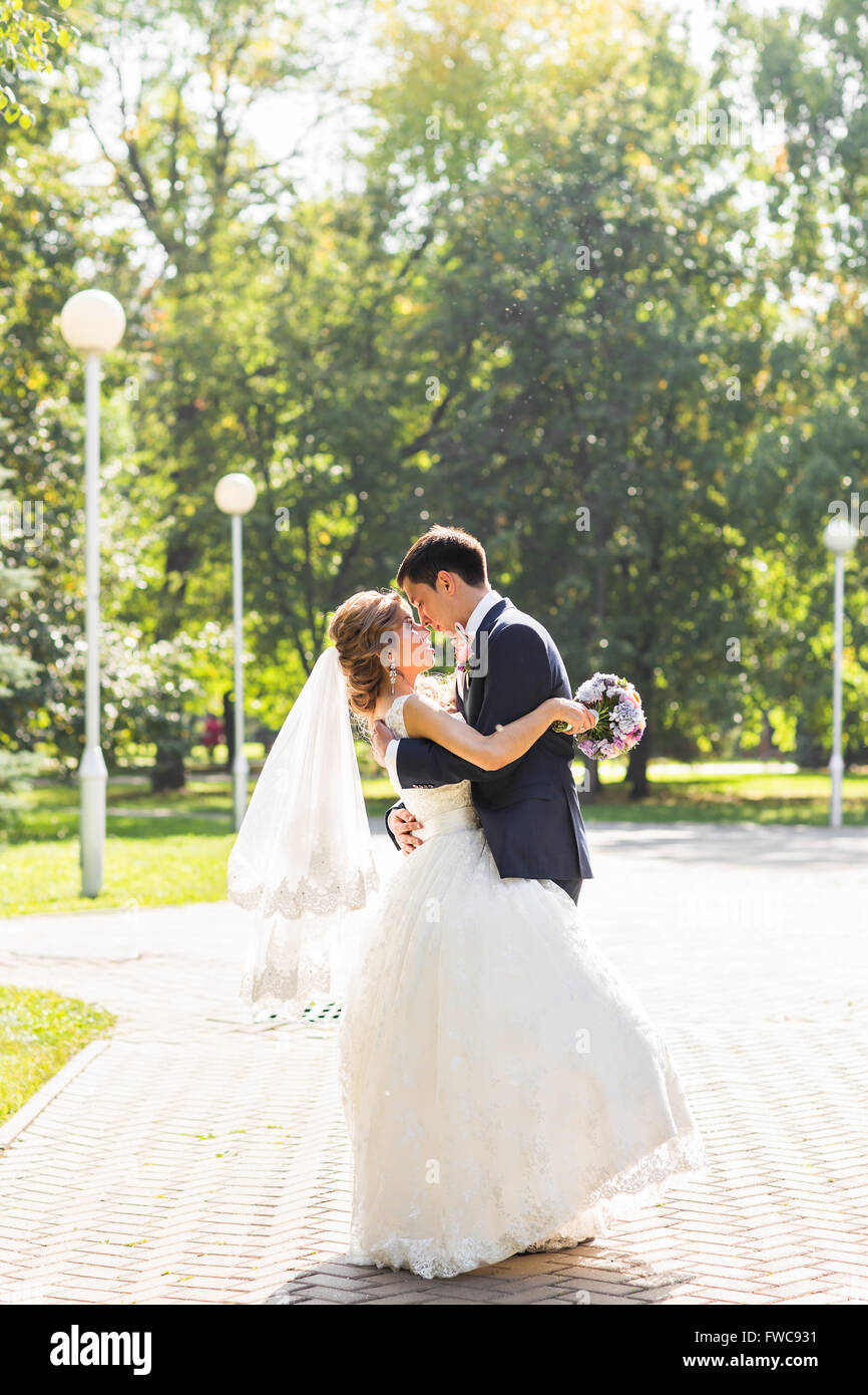 wedding couple hugging, the bride holding a bouquet of flowers, groom ...