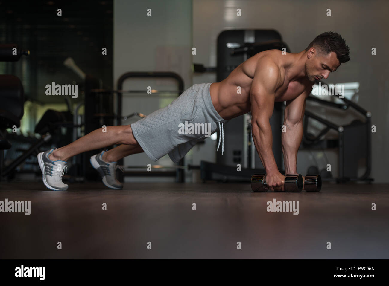 Young Man Athlete Doing Pushups With Dumbbells As Part Of Bodybuilding ...