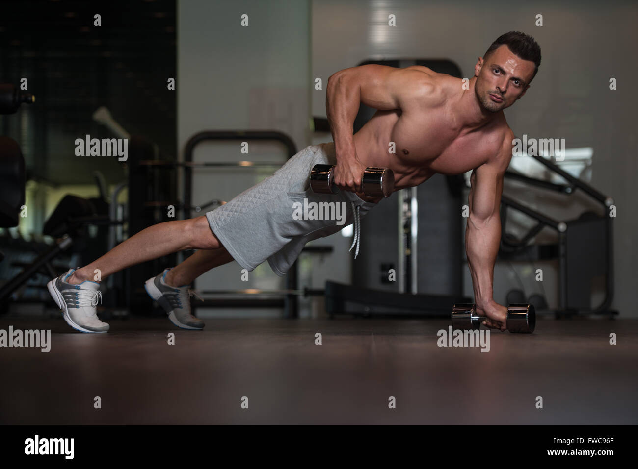 Young Man Athlete Doing Pushups With Dumbbells As Part Of Bodybuilding ...