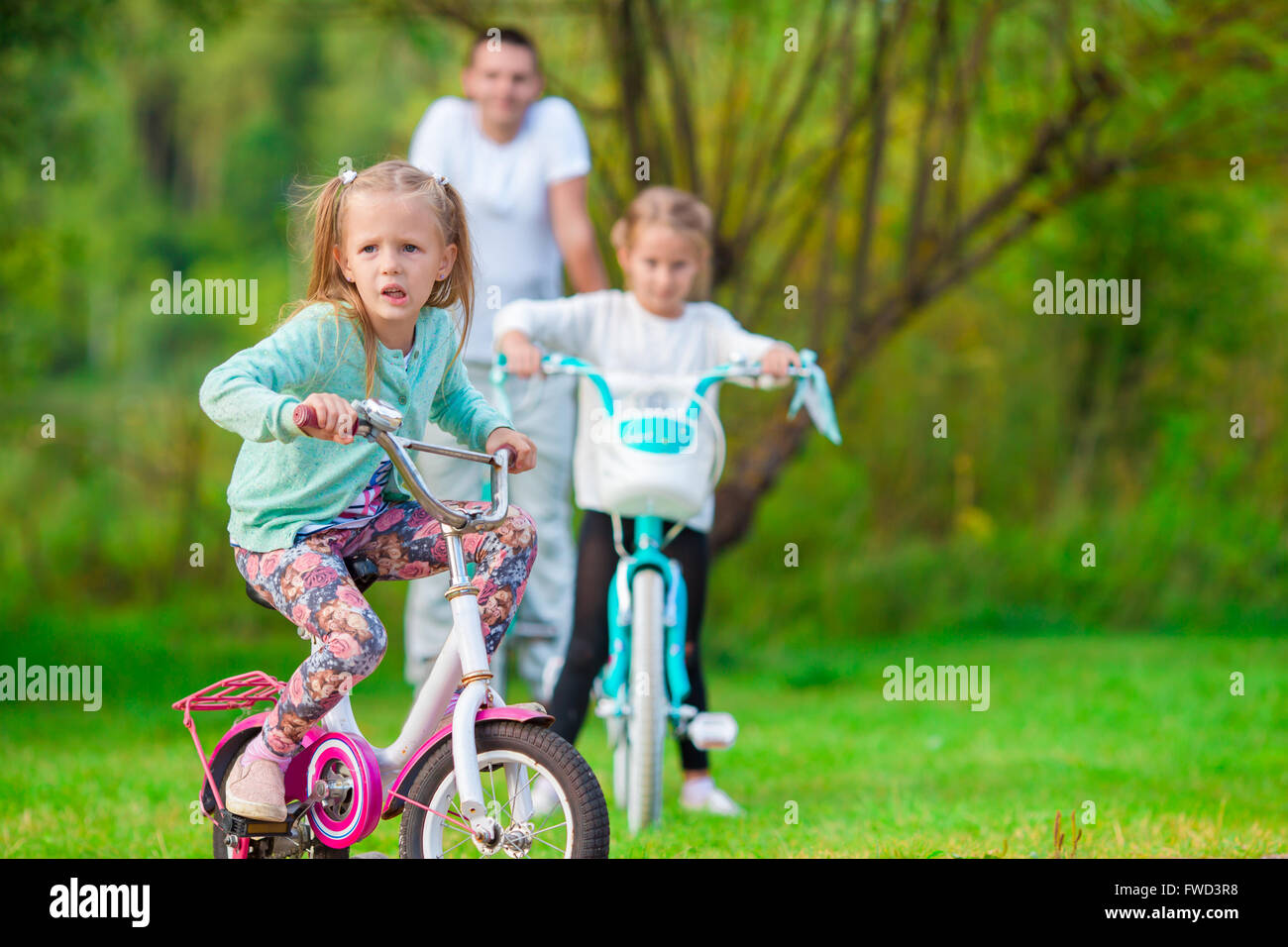 Happy family biking outdoors at the park Stock Photo - Alamy