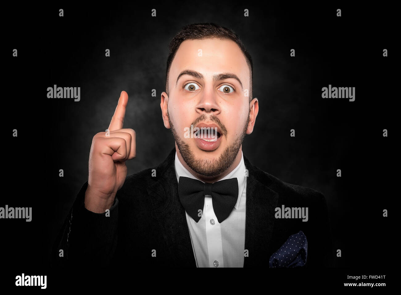 Idea. Young man shows finger up over darck background Stock Photo - Alamy