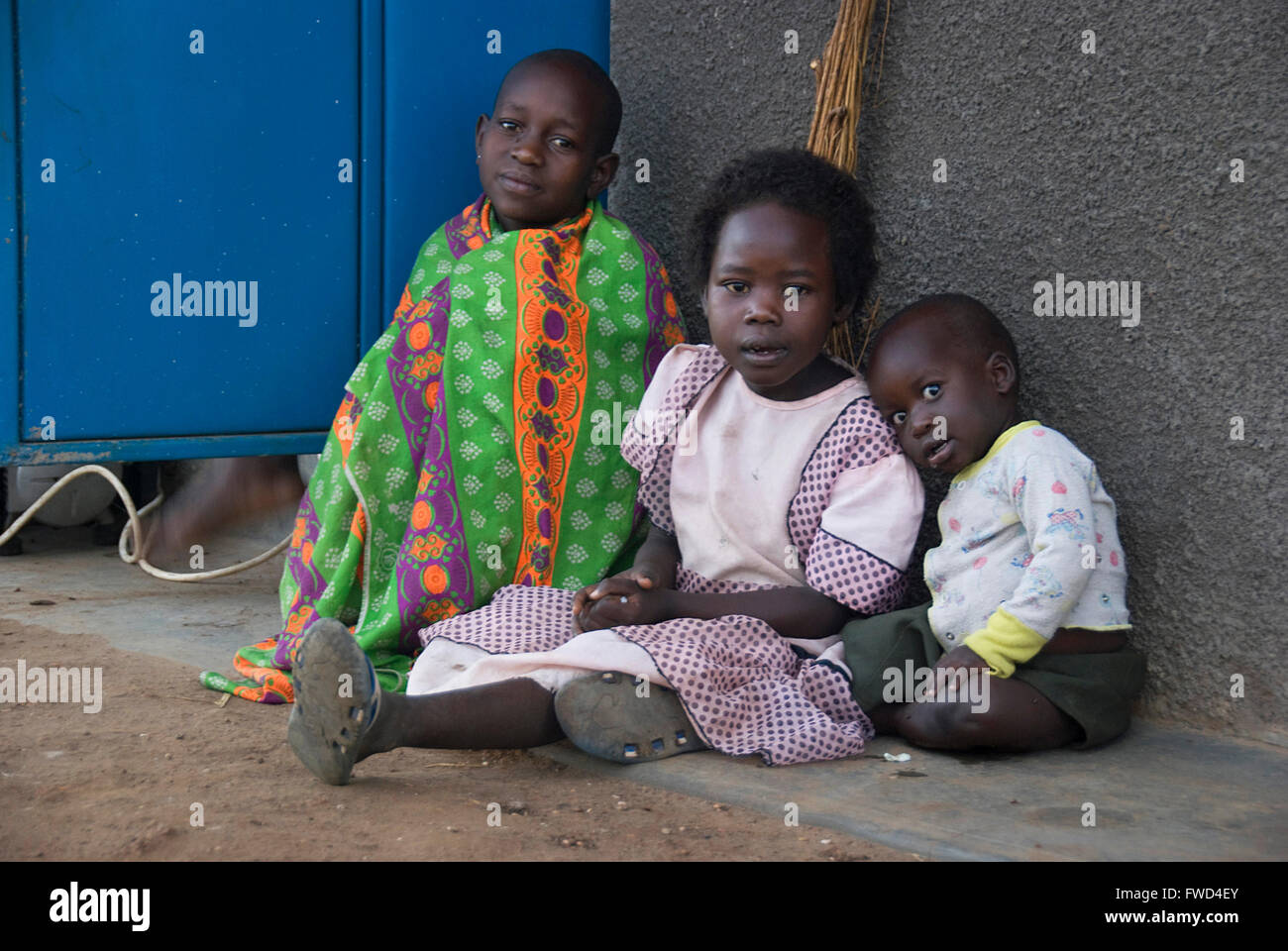 Female villagers and children sit outside in the shade of the church at ...