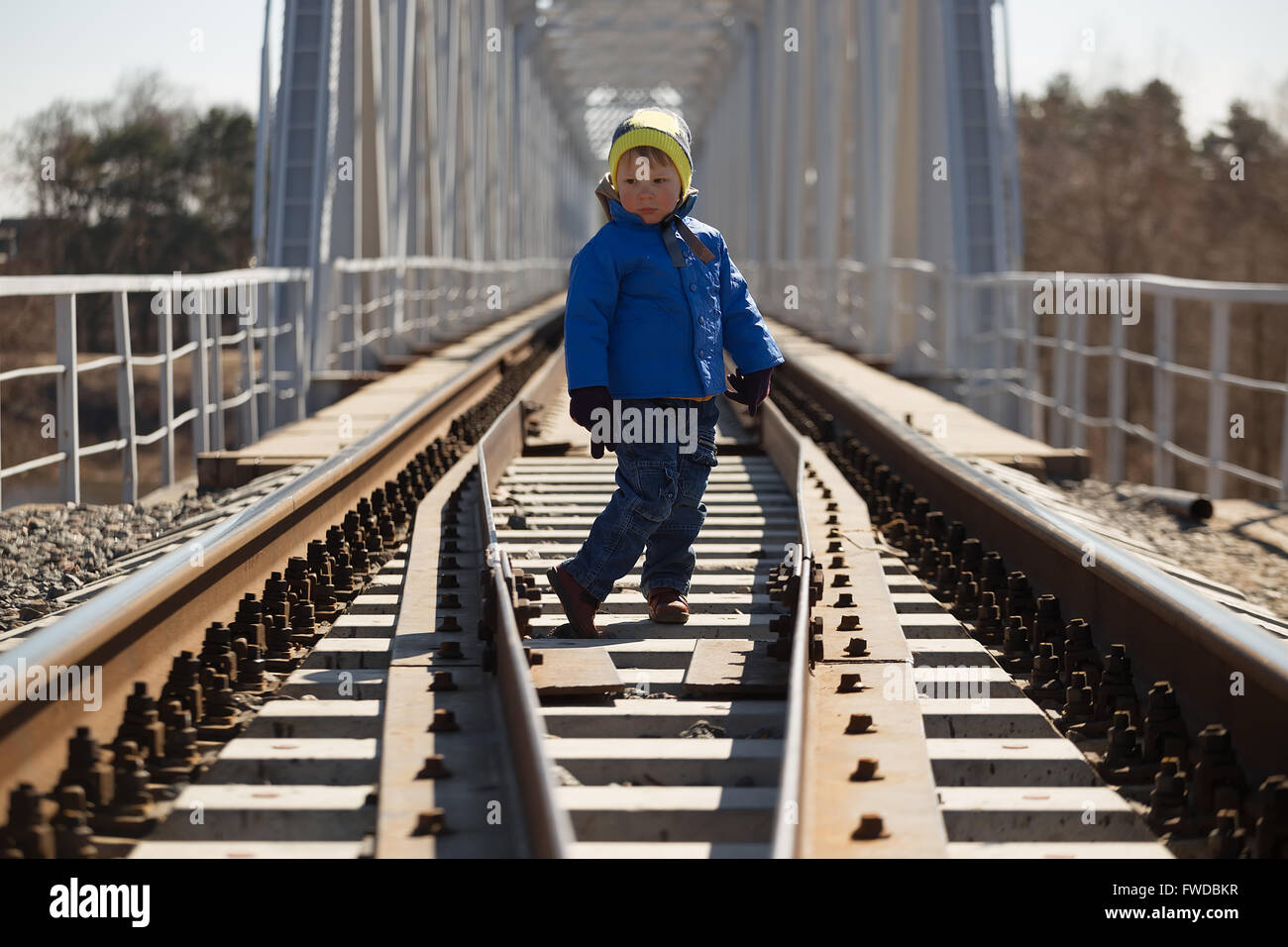 Portrait of a little boy sitting on the rails in the daytime. Belarus ...