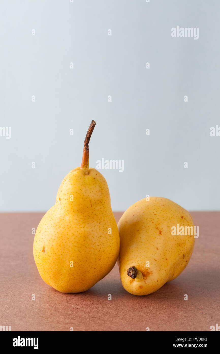 Two whole yellow Corella pears on wooden surface. Vertical image with ...