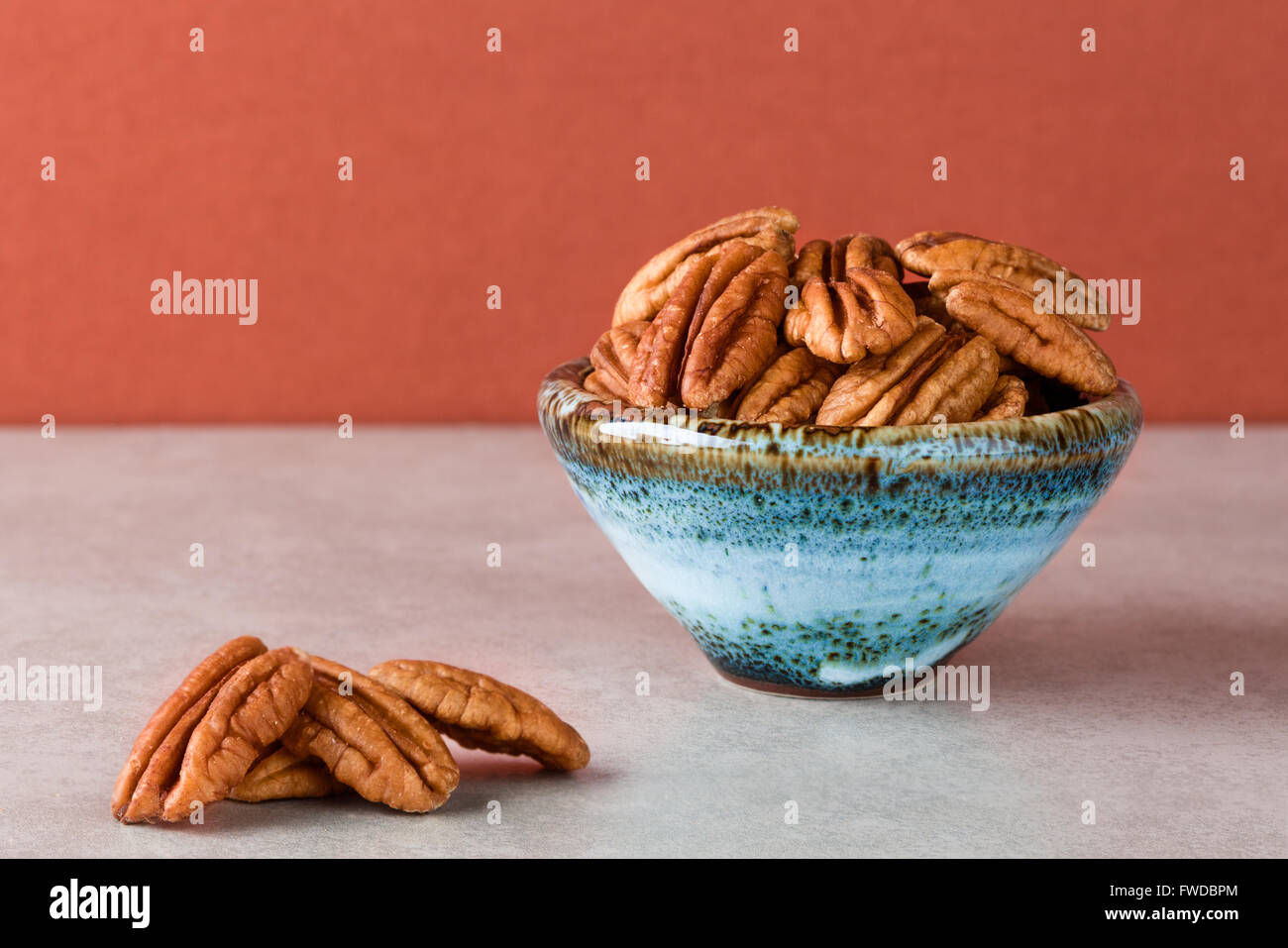 Pecans on marble surface and in ceramic bowl with brown background ...
