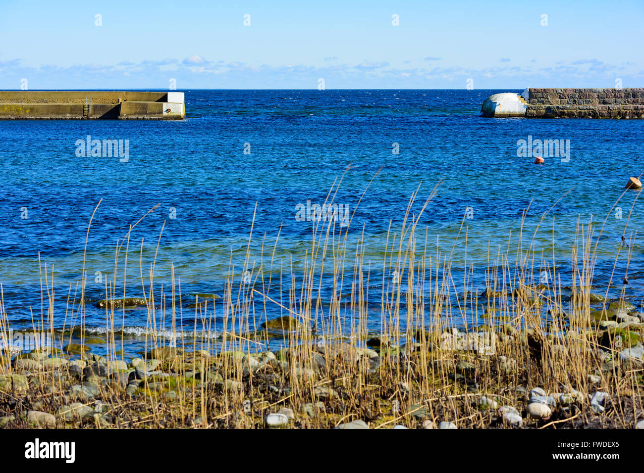 Two stone piers meet in a harbor, making an opening for incoming and ...