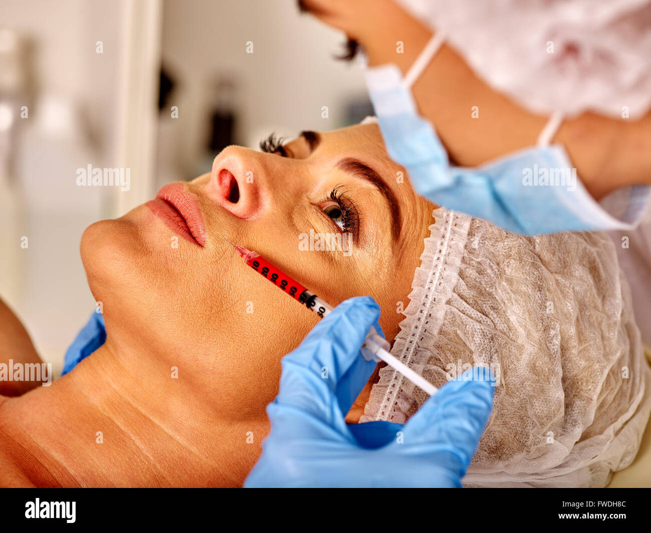 Woman middle-aged into spa salon with beautician. Female giving botox ...