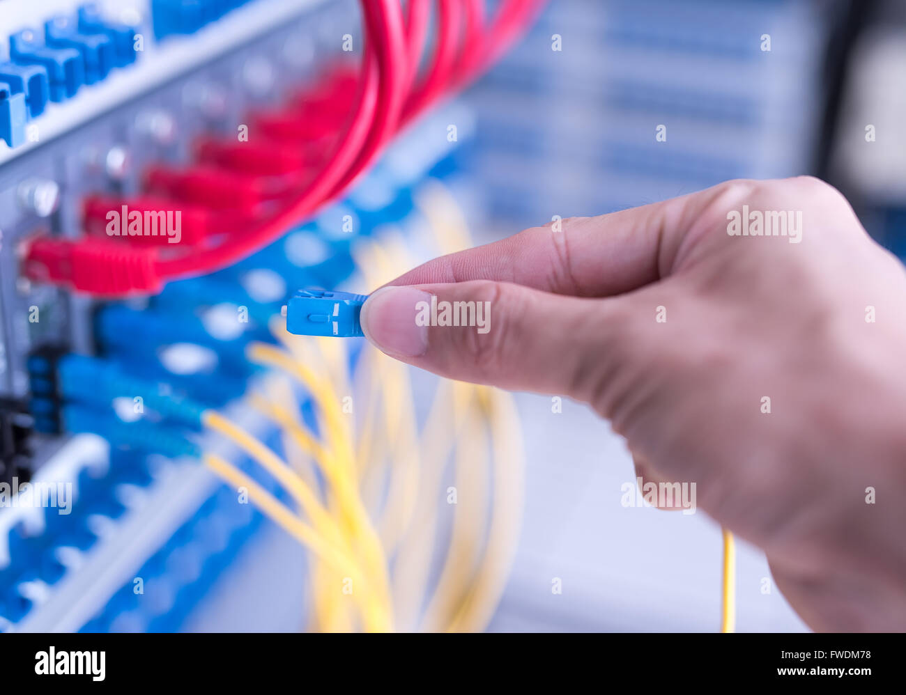 man working in network server room with fiber optic hub for digital ...