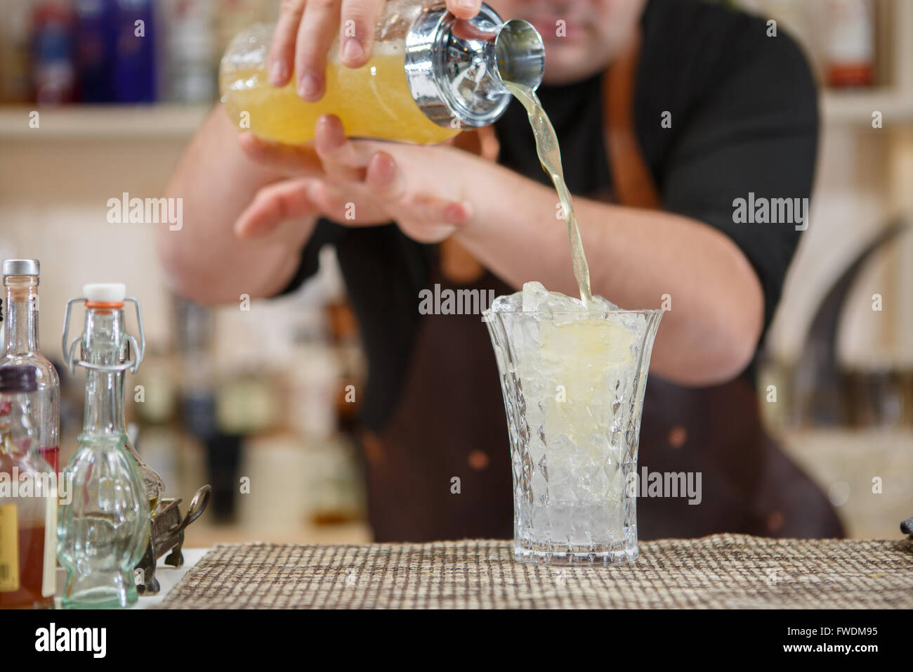 Bartender pouring cocktail into glass at the bar Stock Photo - Alamy
