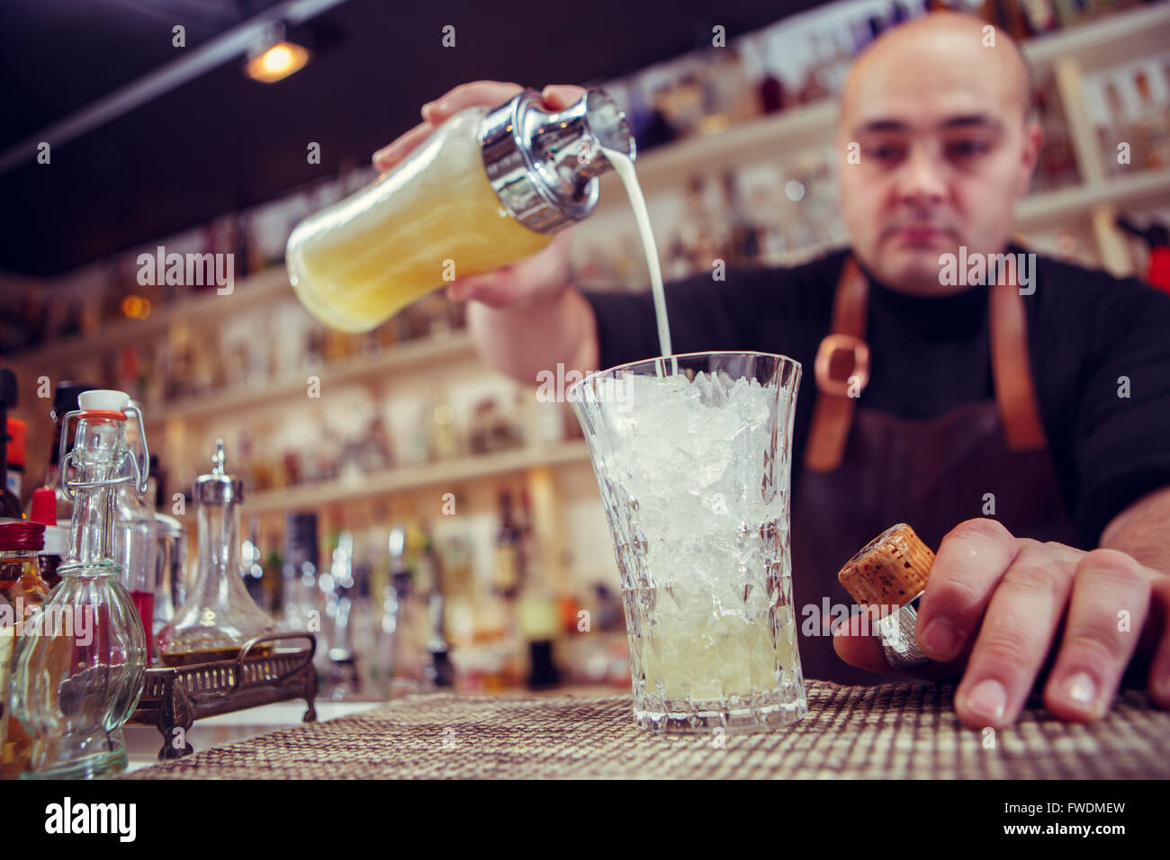 Bartender pouring cocktail into glass at the bar Stock Photo - Alamy