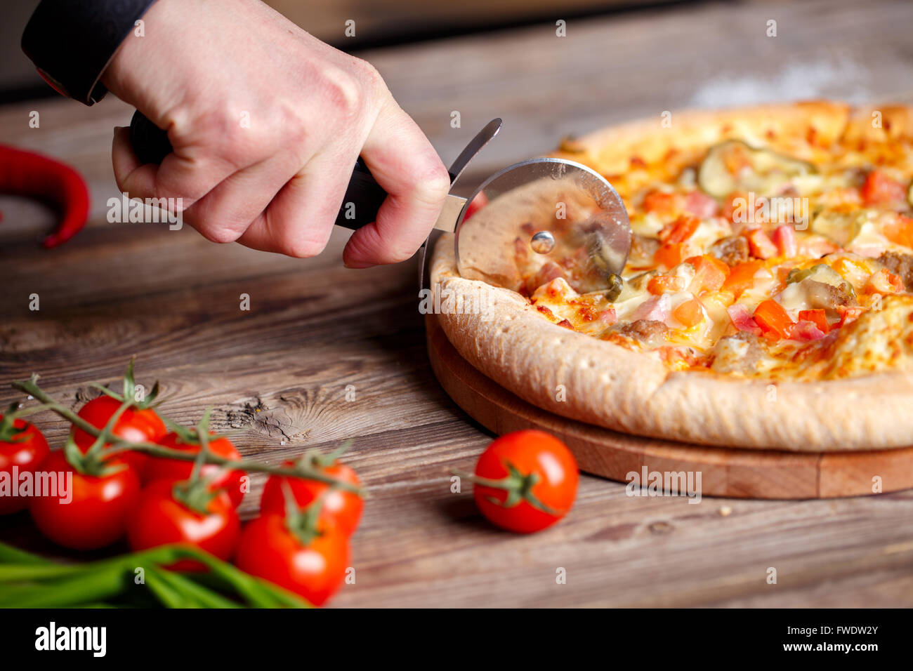 Slicing fresh pizza with roller knife Stock Photo - Alamy