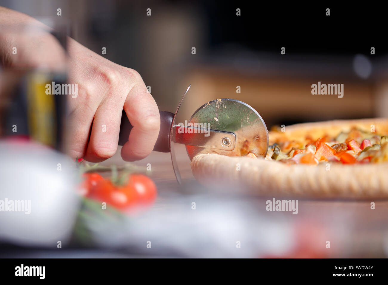 Slicing fresh pizza with roller knife Stock Photo - Alamy