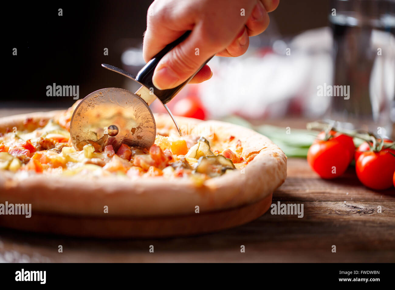 Slicing fresh pizza with roller knife Stock Photo - Alamy