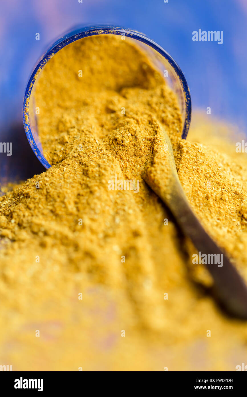 Curry powder spilling from a blue glass Stock Photo - Alamy