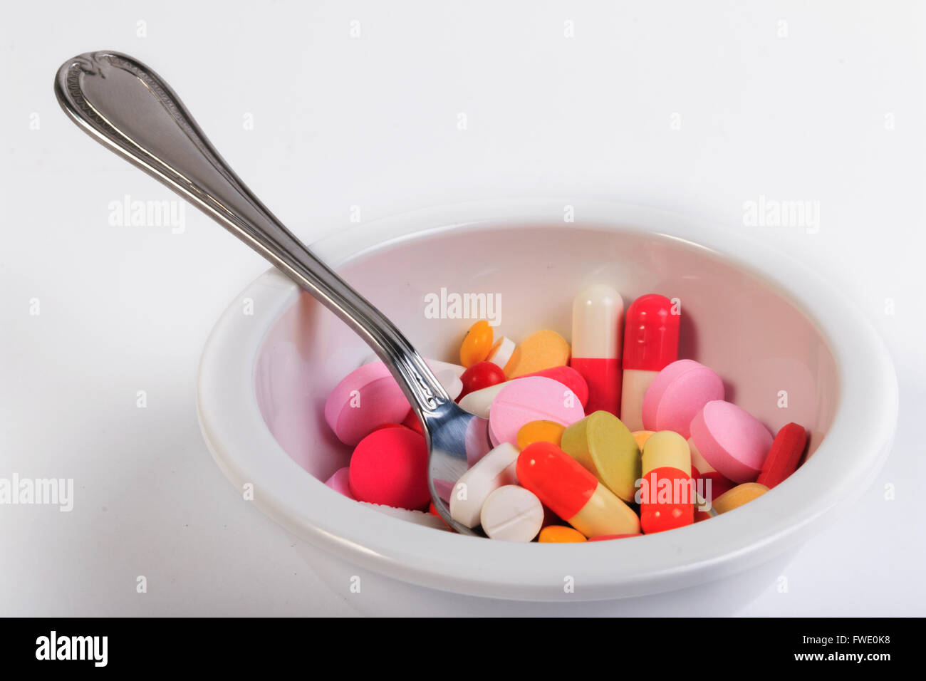 Many colored pills and capsules in a bowl with a spoon Stock Photo - Alamy