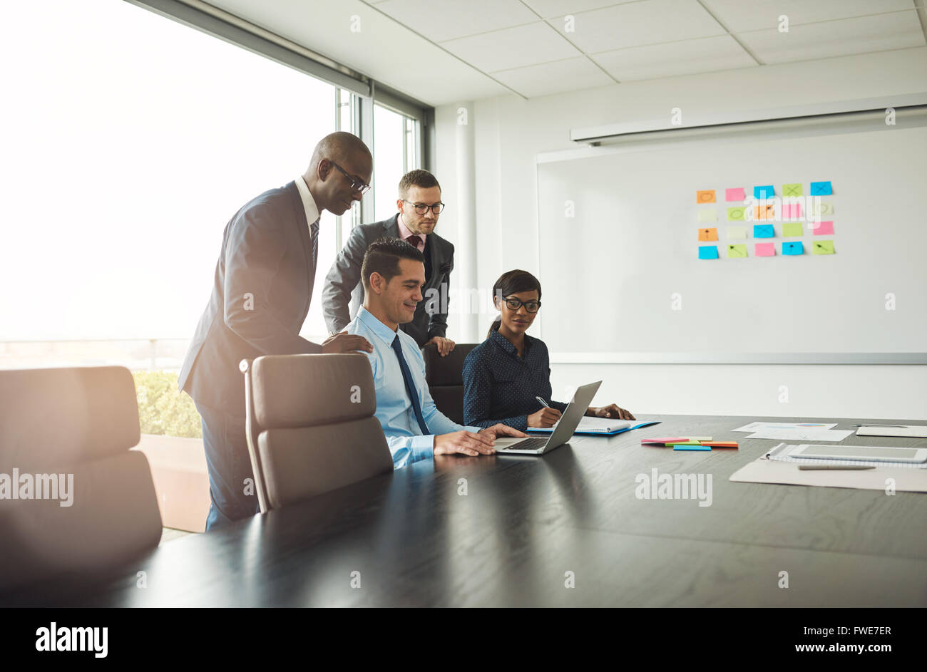 Group of four Black and white young business people at conference table ...