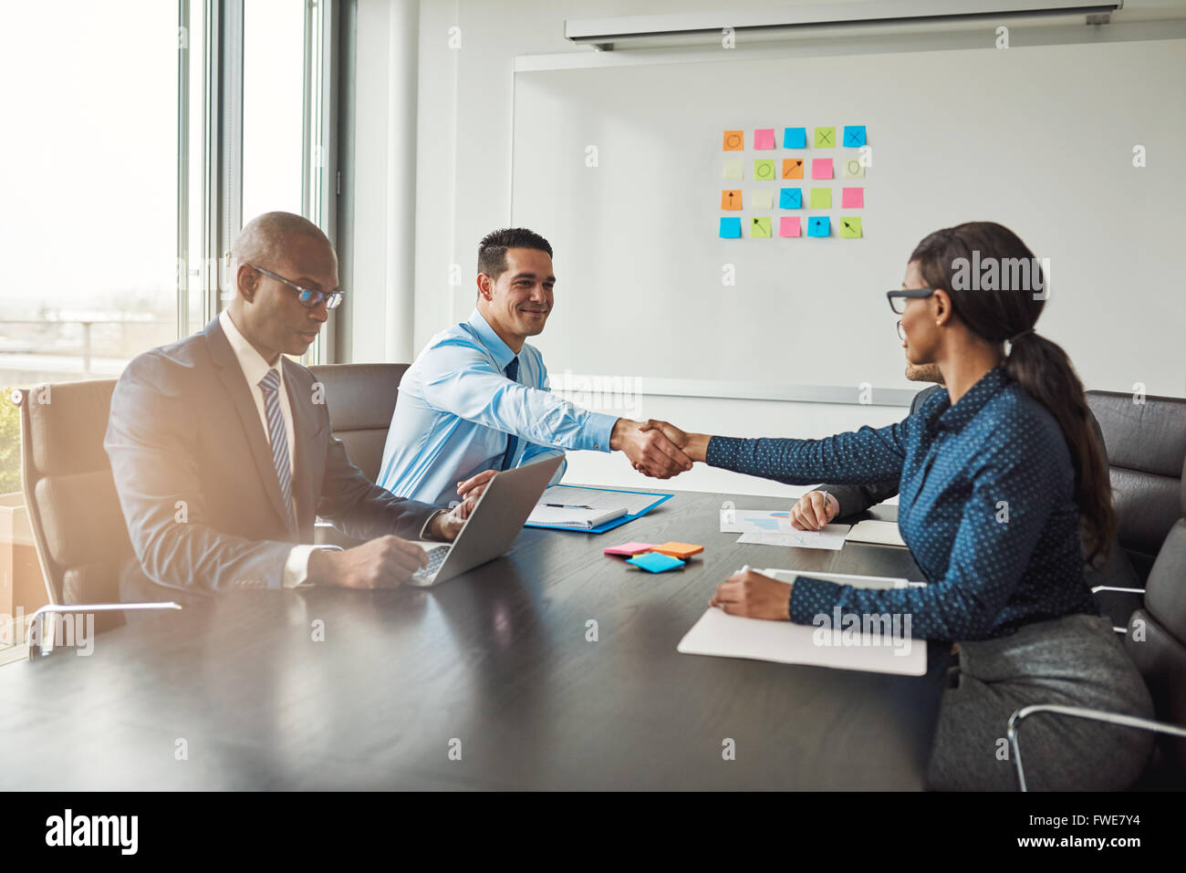 Two business colleagues shaking hands across the table in ...