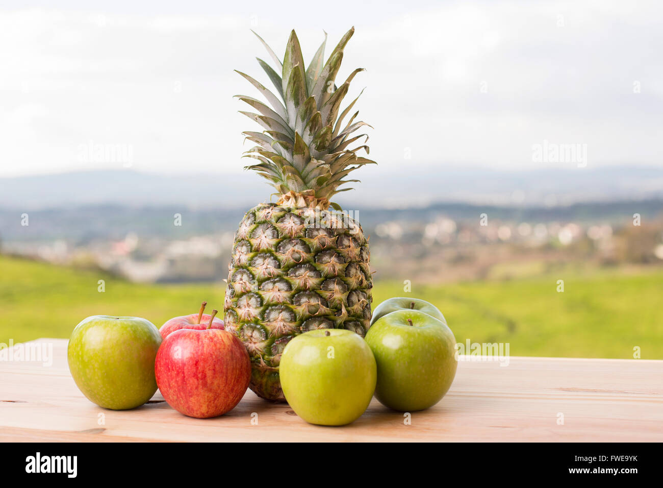 Pineapple and apple on wood table, outdoor Stock Photo - Alamy