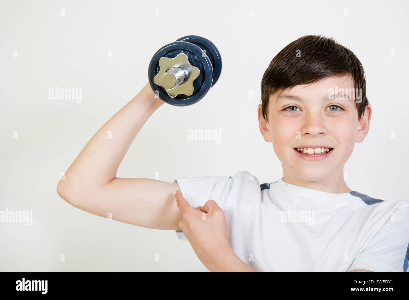 Happy young boy lifting a dumbbell, pointing at his bicep Stock Photo ...