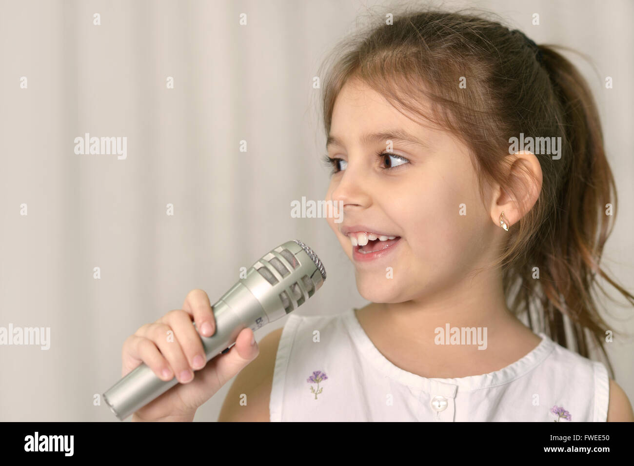 Beautiful little girl with microphone Stock Photo - Alamy