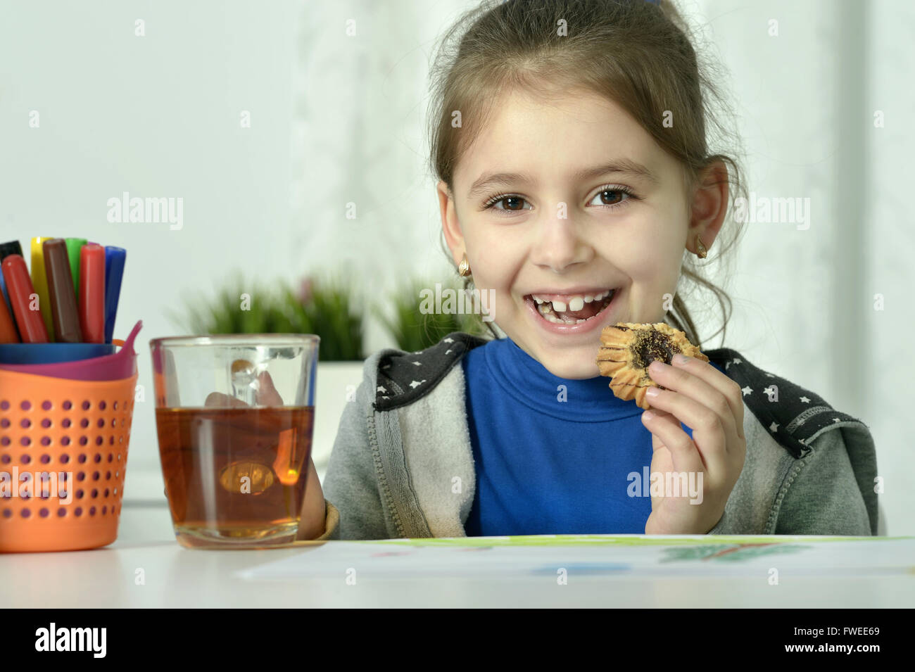 girl drinking tea and eating cookie Stock Photo - Alamy