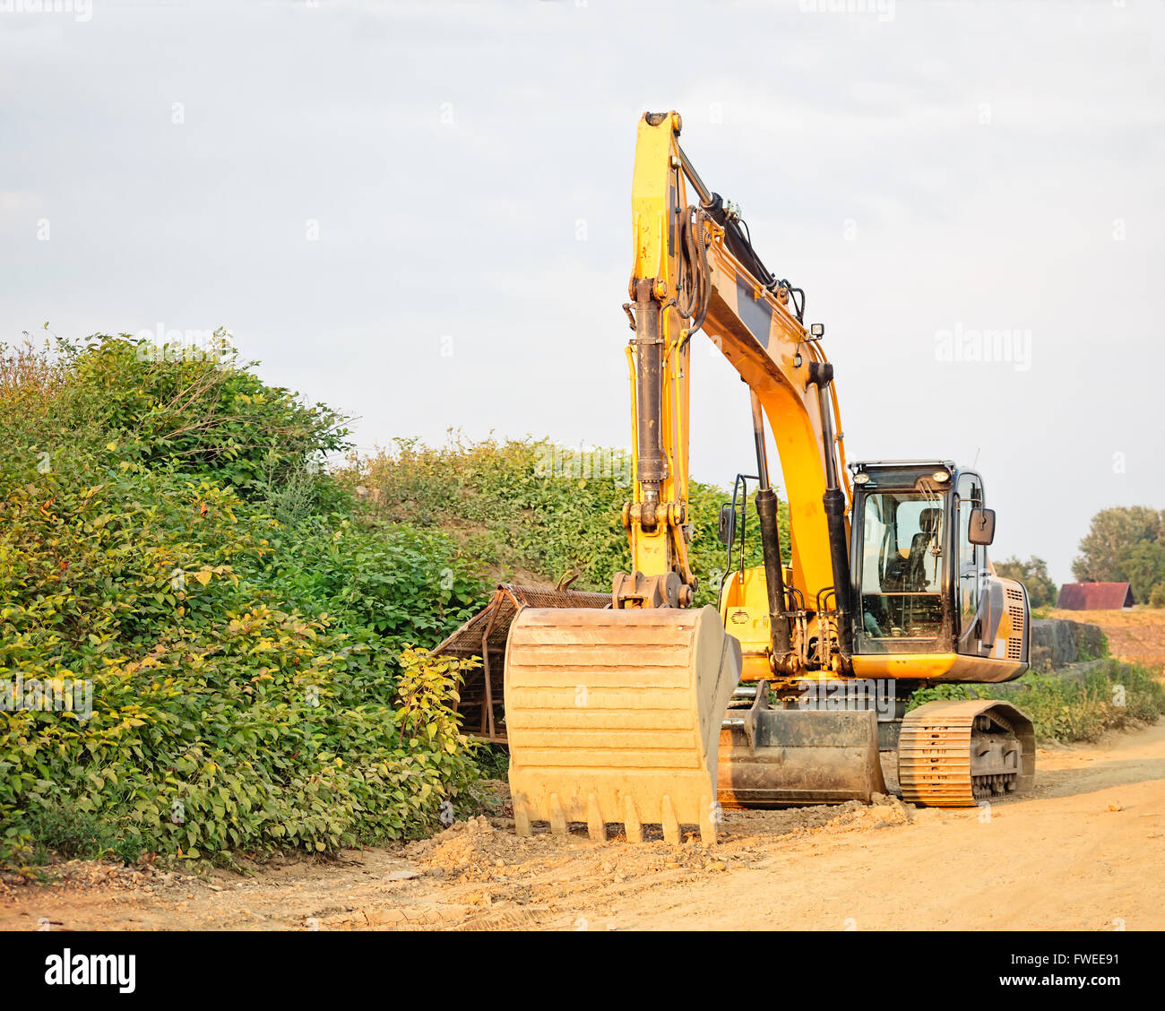 Yellow crawler excavator on the side of a dirt road Stock Photo - Alamy