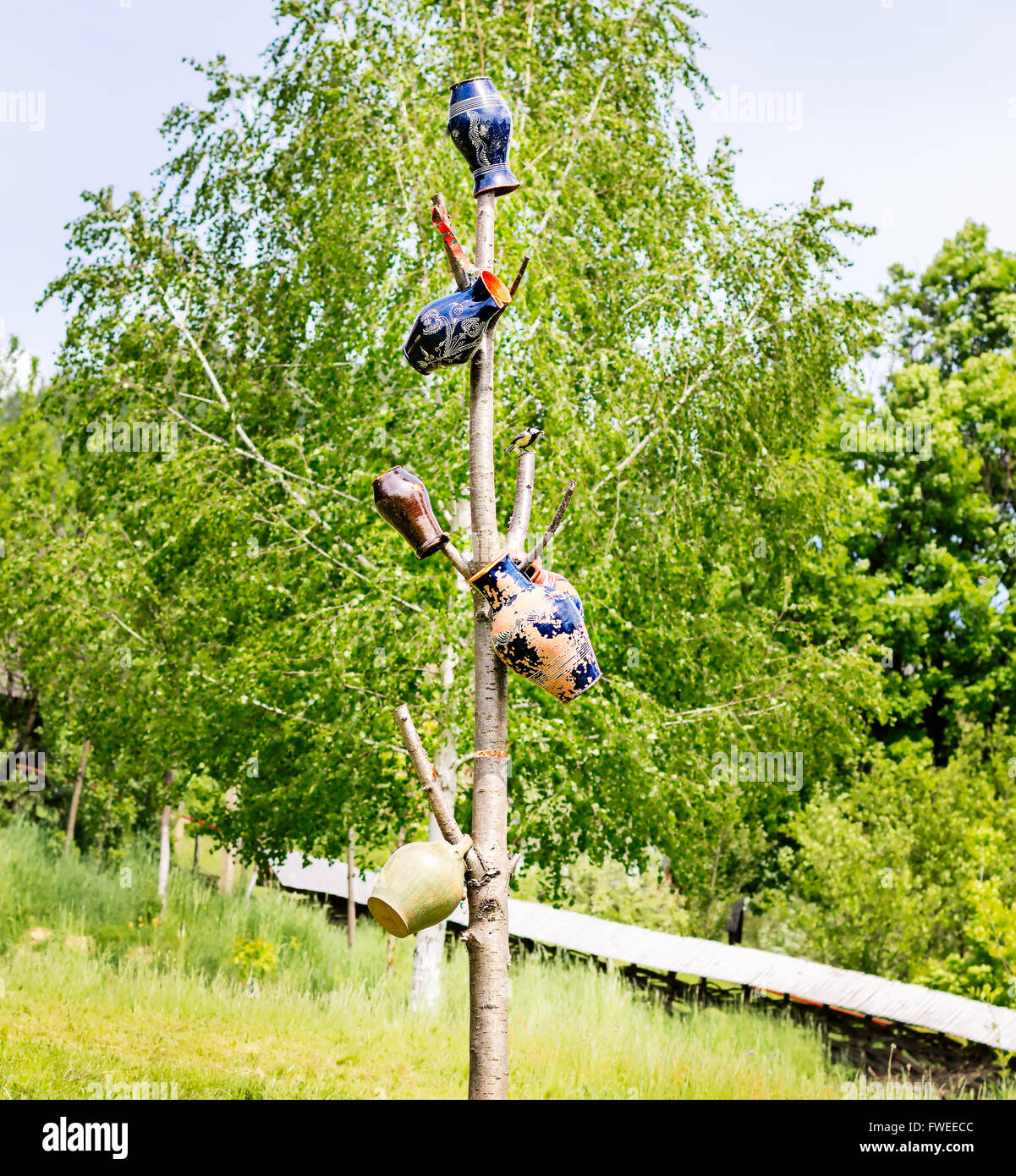 Colorful handmade and hand painted pots hanging on branches of a tree ...