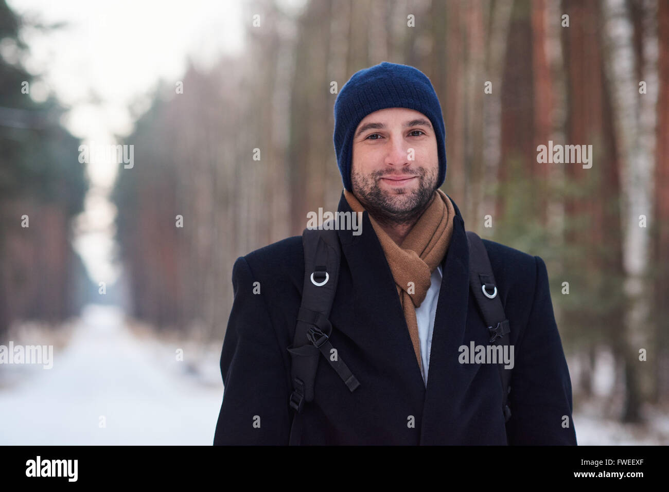 Positive young man with a sweet smile and stubble, wearing warm ...