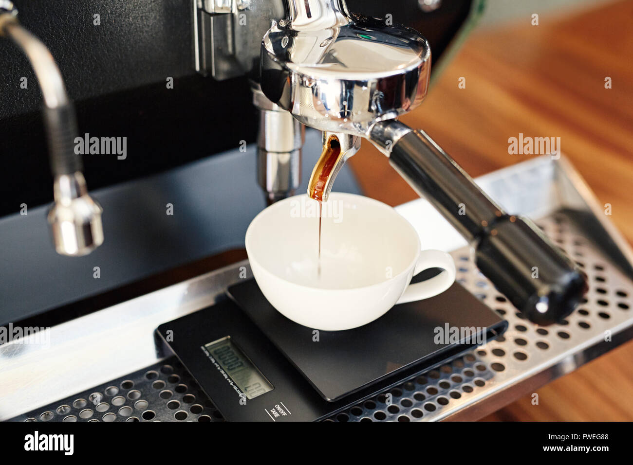 Shiny portafilter attached to an espresso machine, busy pouring coffee ...