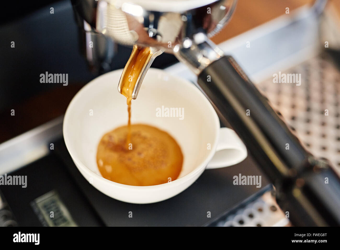 Closeup of fresh coffee pouring from the spout of a portafilter that is ...