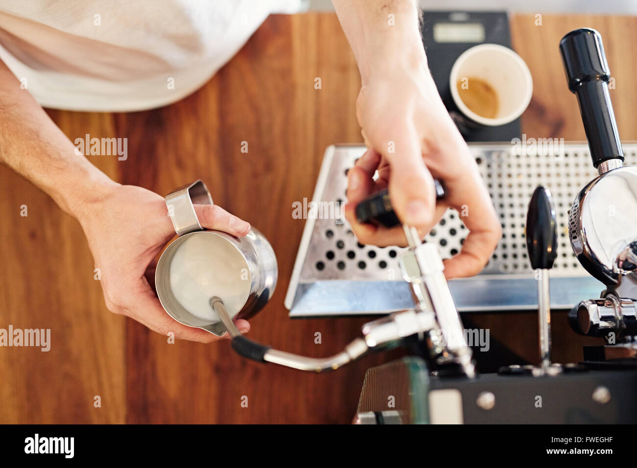 Overhead shot of a barista's hands using an espresso machine to steam ...