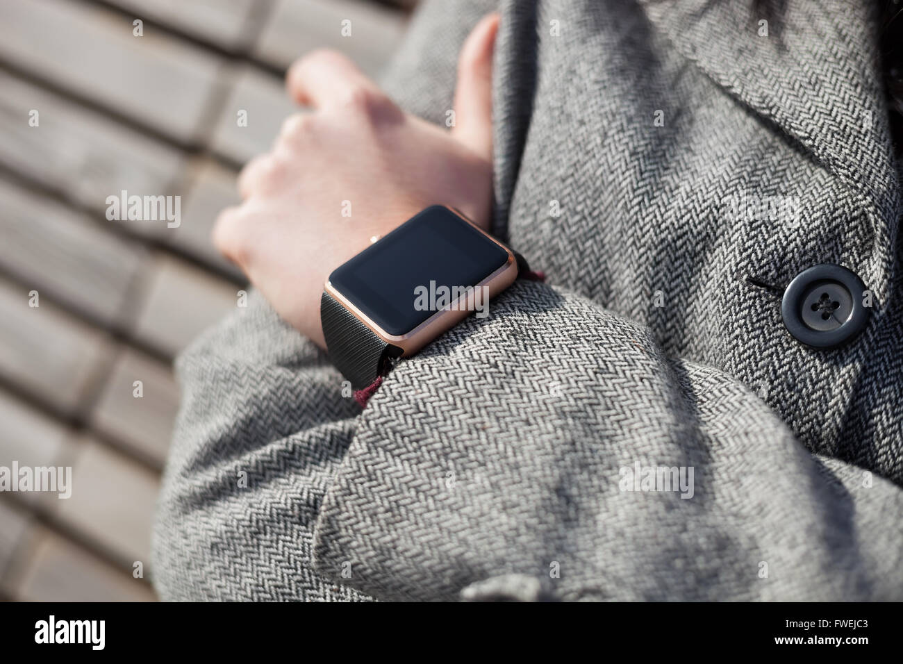 Woman in grey coat wearing modern smart wrist watch. This person is ...