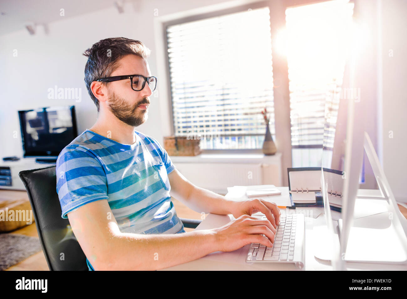 Man sitting at desk working from home on computer Stock Photo - Alamy