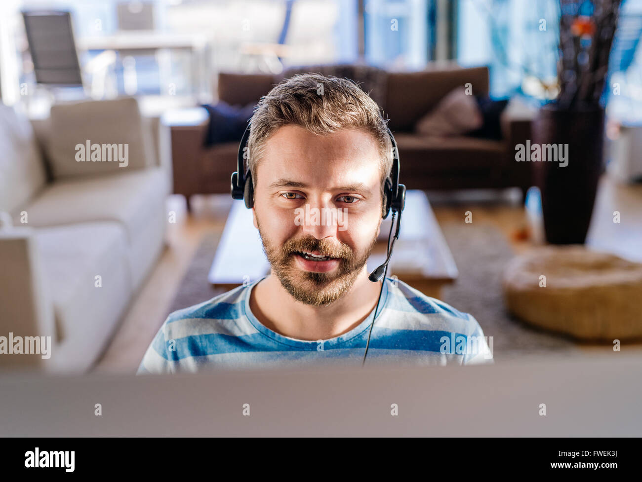 Man working from home on computer, wearing headset Stock Photo - Alamy