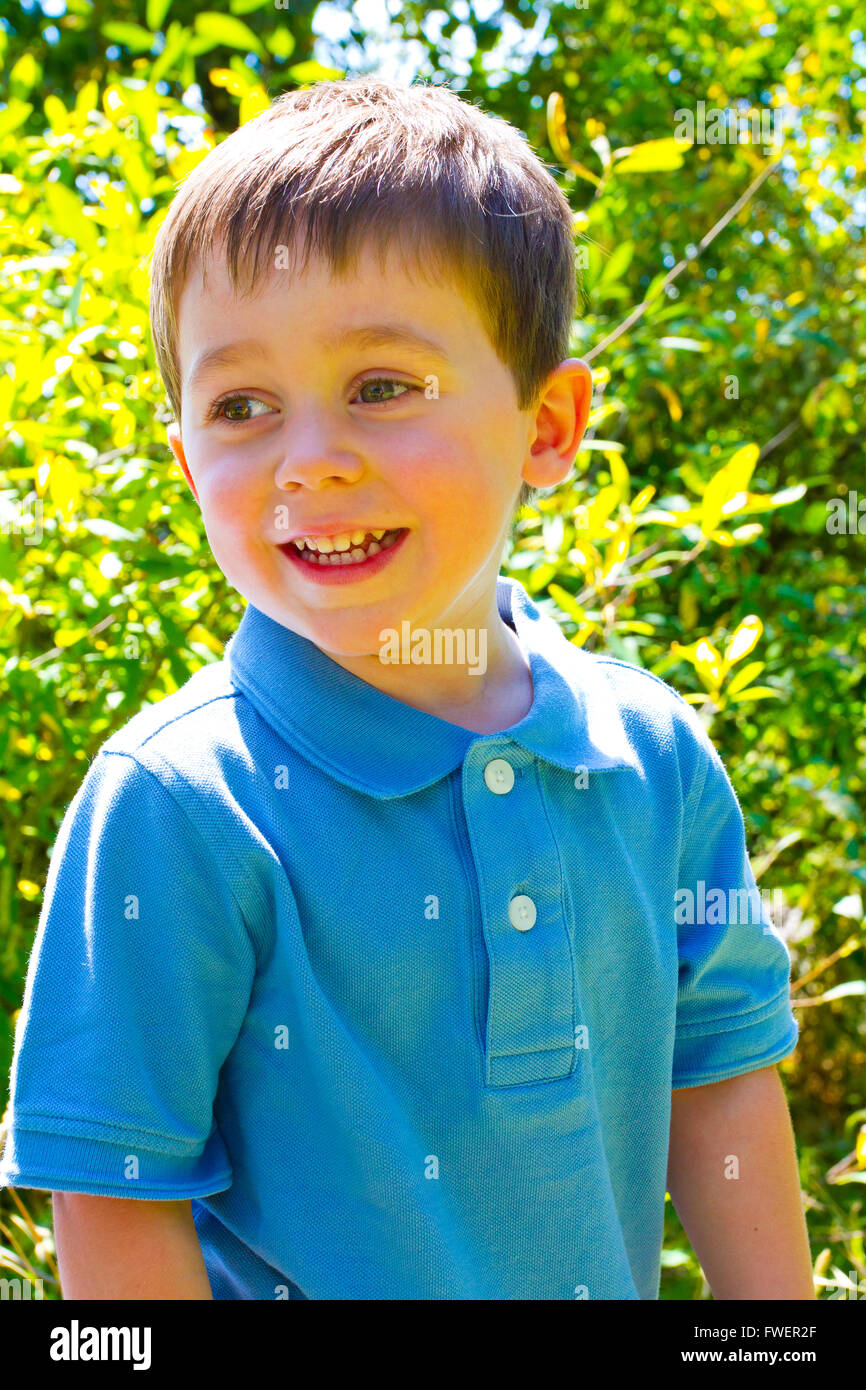 A young boy is playing outdoors while wearing a blue polo shirt Stock ...