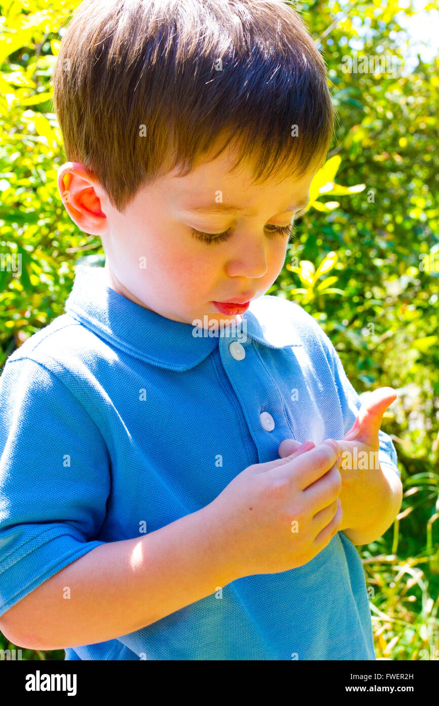 A young boy is playing outdoors while wearing a blue polo shirt Stock ...