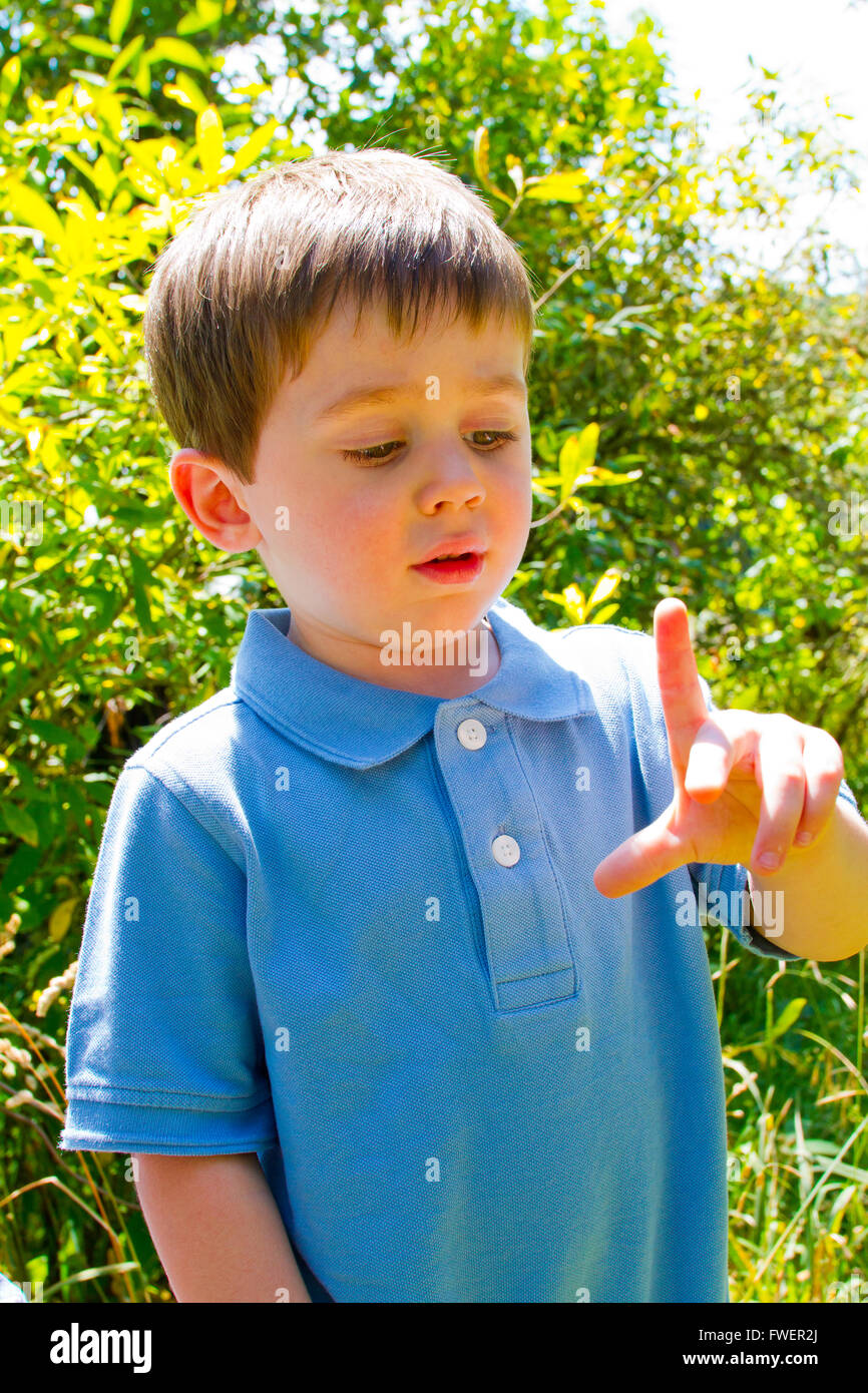 A young boy is playing outdoors while wearing a blue polo shirt Stock ...
