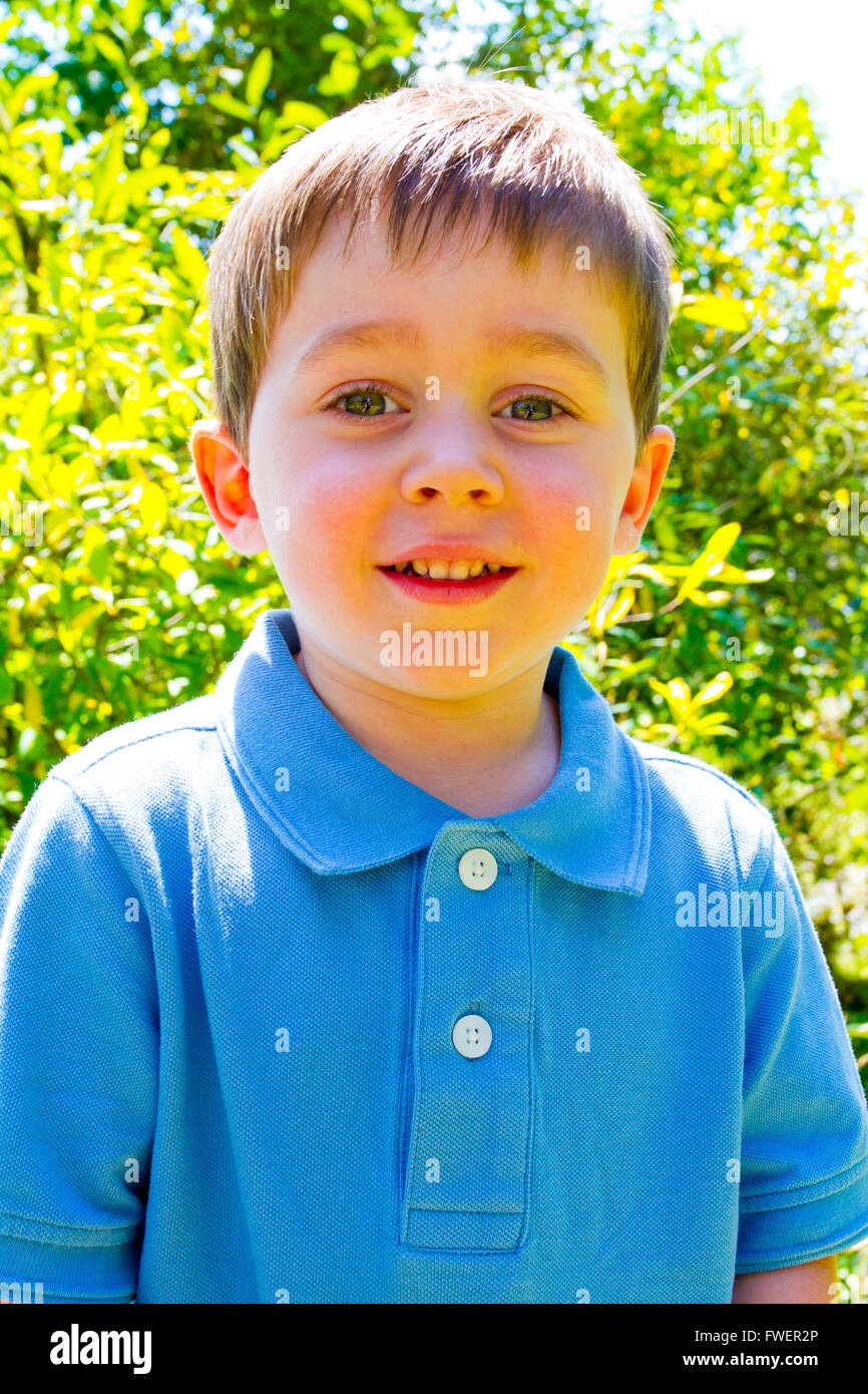 A young boy is playing outdoors while wearing a blue polo shirt Stock ...