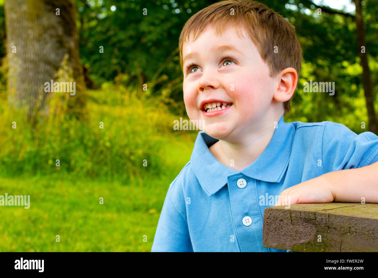 A young boy is playing outdoors while wearing a blue polo shirt Stock ...